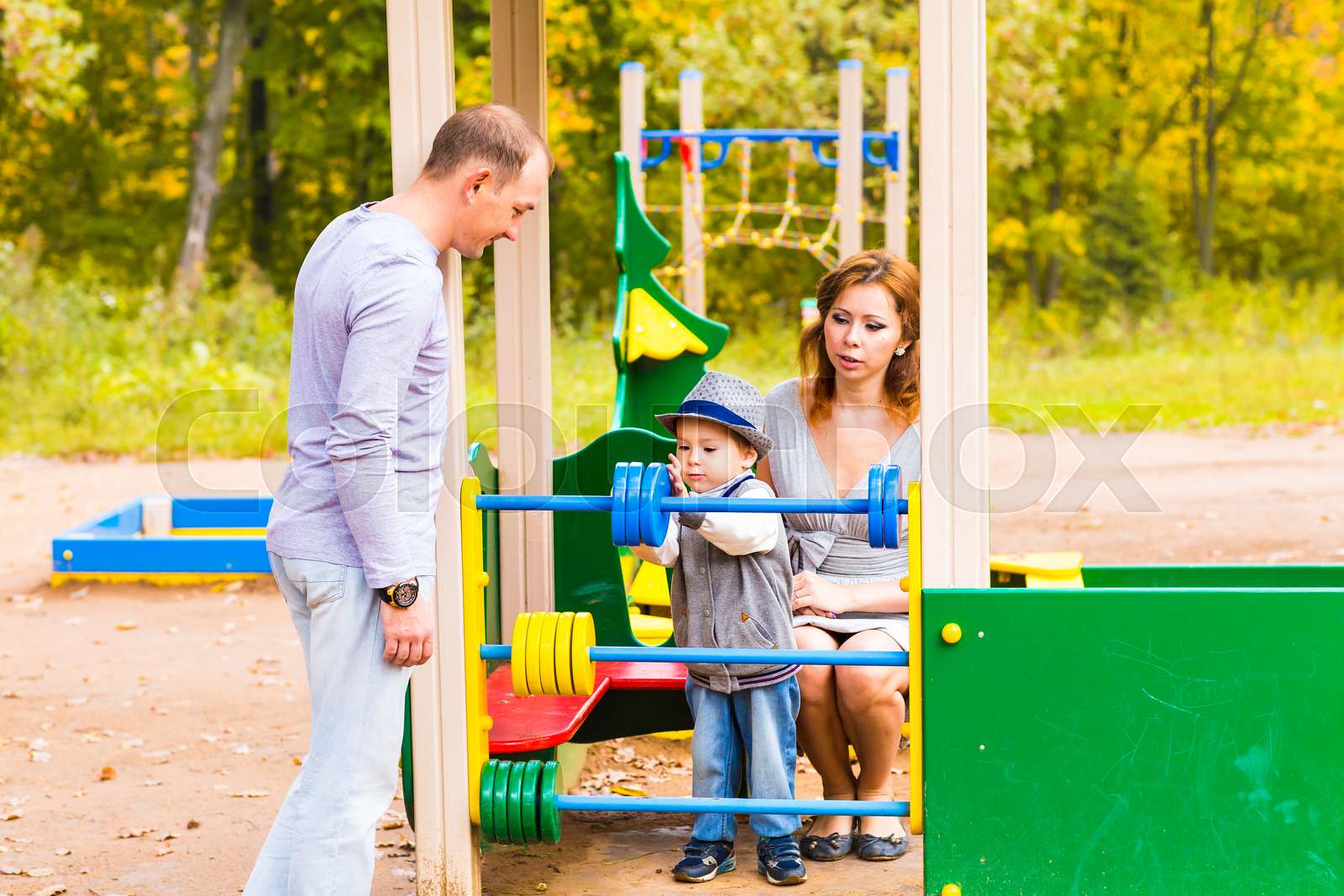 playful child with parents at the playground outdoor. Mom, dad and kid ...
