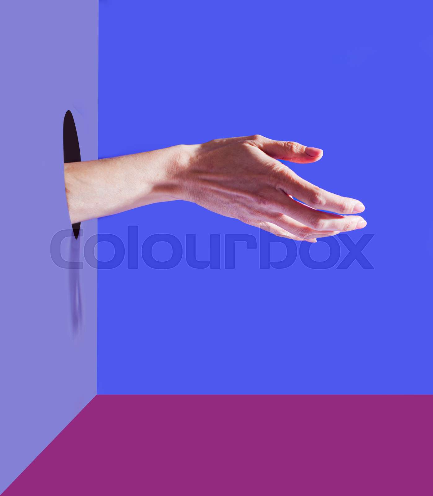 Hand sticks out from the hole in a wall | Stock image | Colourbox