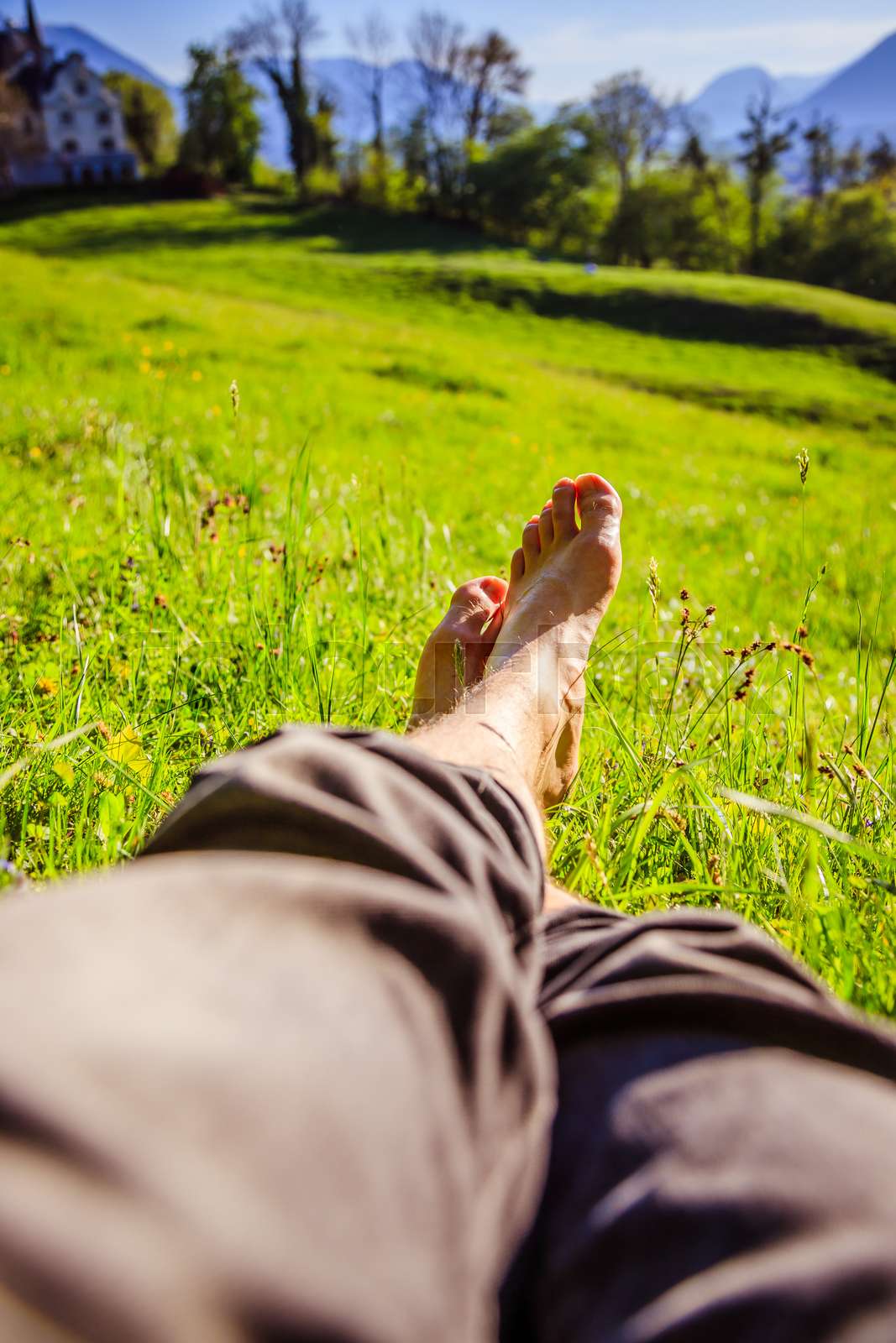 Chilling in the green grass: Legs of a young man, relaxing, summertime ...