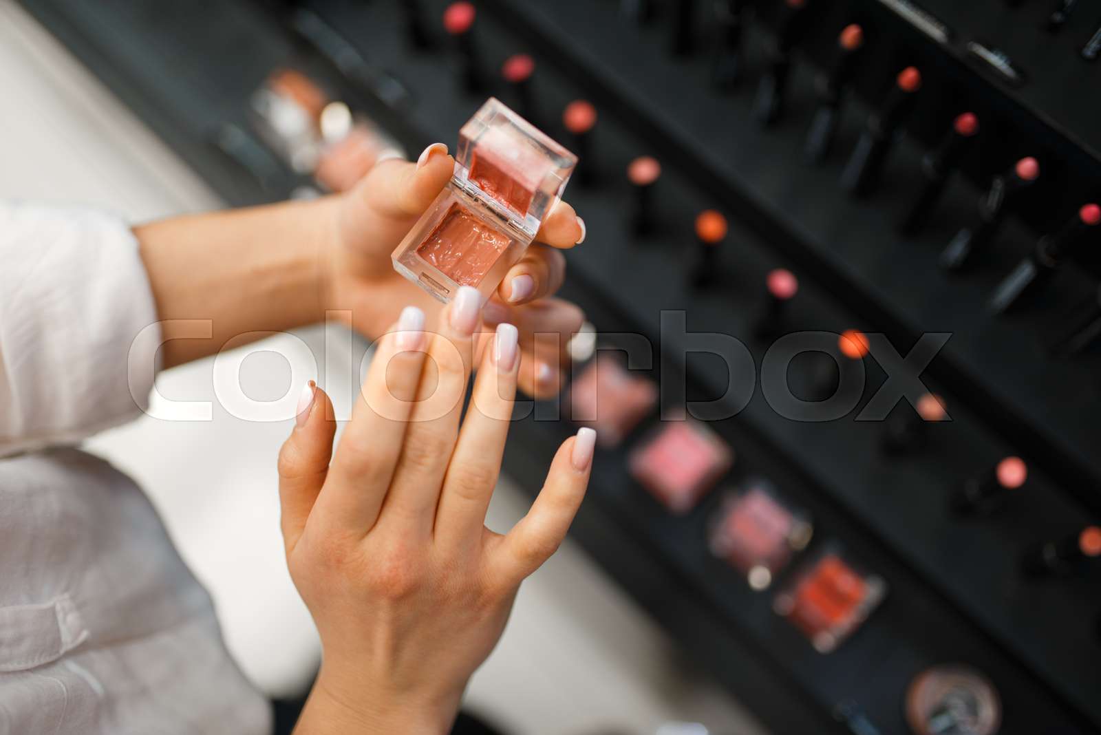 Woman holds lipstick tester in cosmetics store | Stock image | Colourbox
