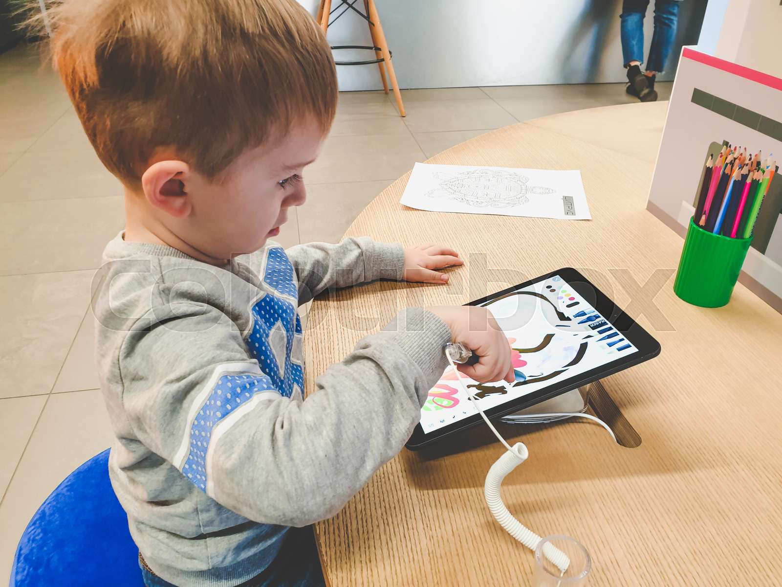 Toned image of child using tablet computer for drawing in kindergarten ...