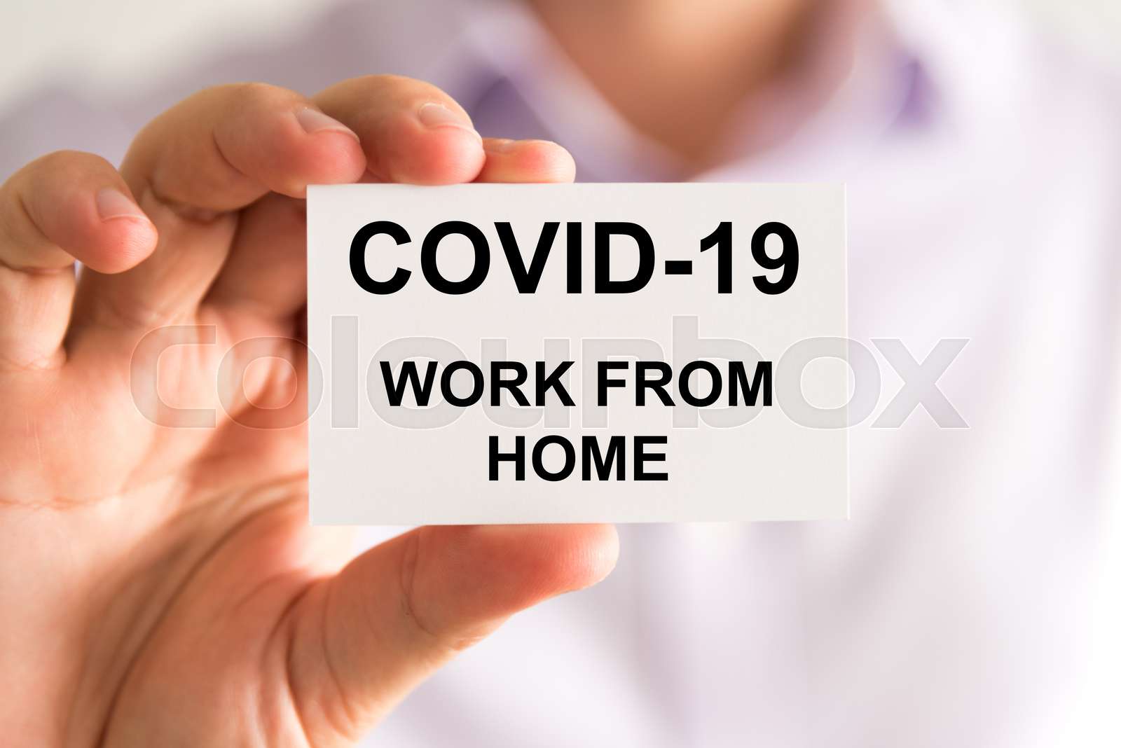 Businessman holding Covid-19 Work From Home card | Stock image | Colourbox