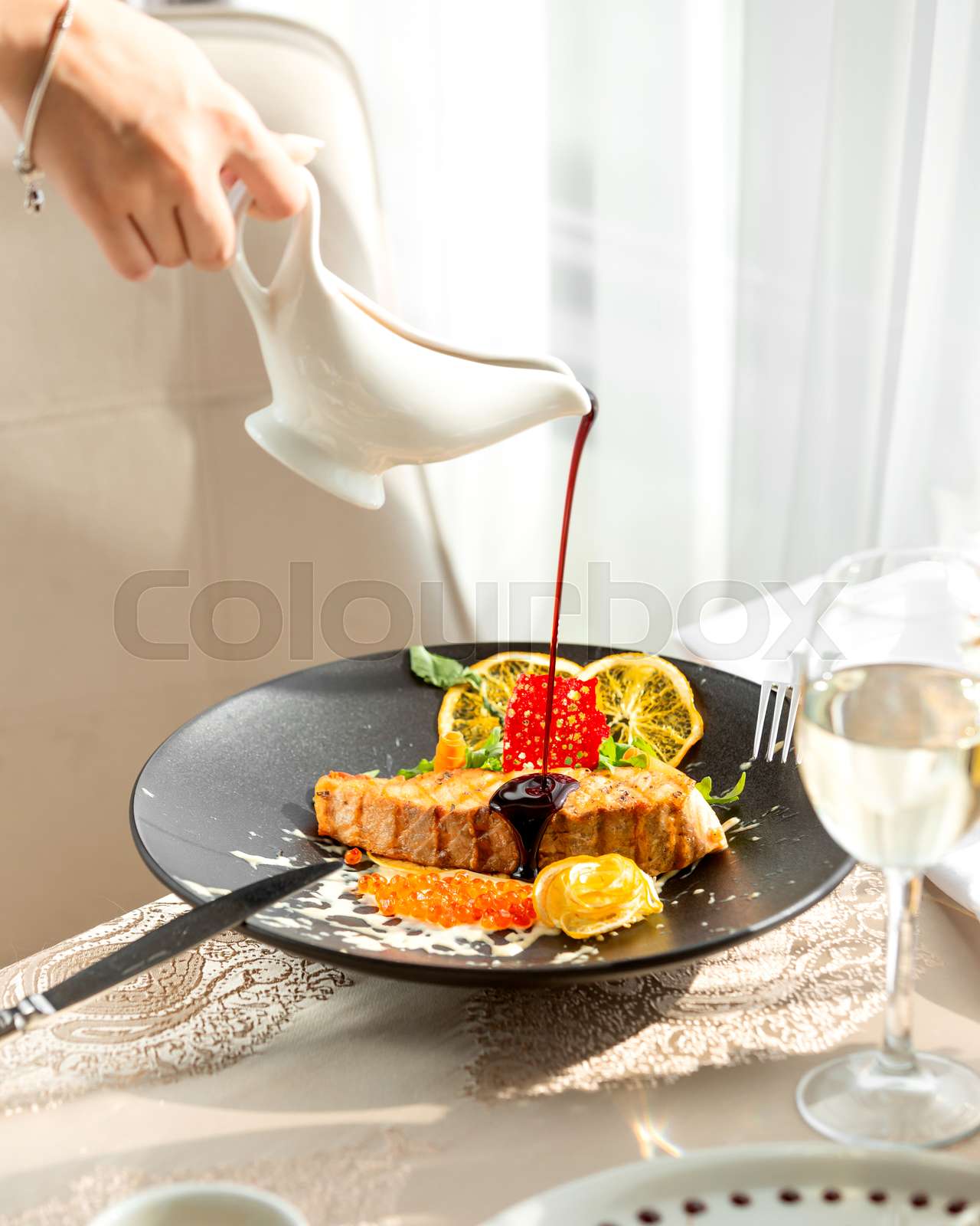Woman pouring nar sharab on grilled salmon | Stock image | Colourbox