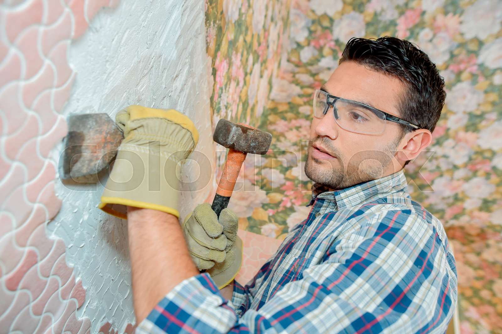 Builder chipping tiles off of a wall | Stock image | Colourbox