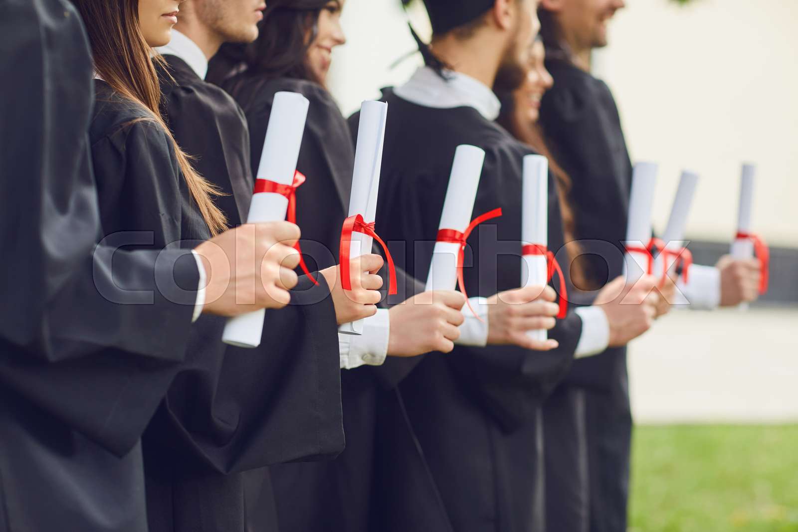 Scrolls of diplomas in the hands of a group of graduates. | Stock image ...