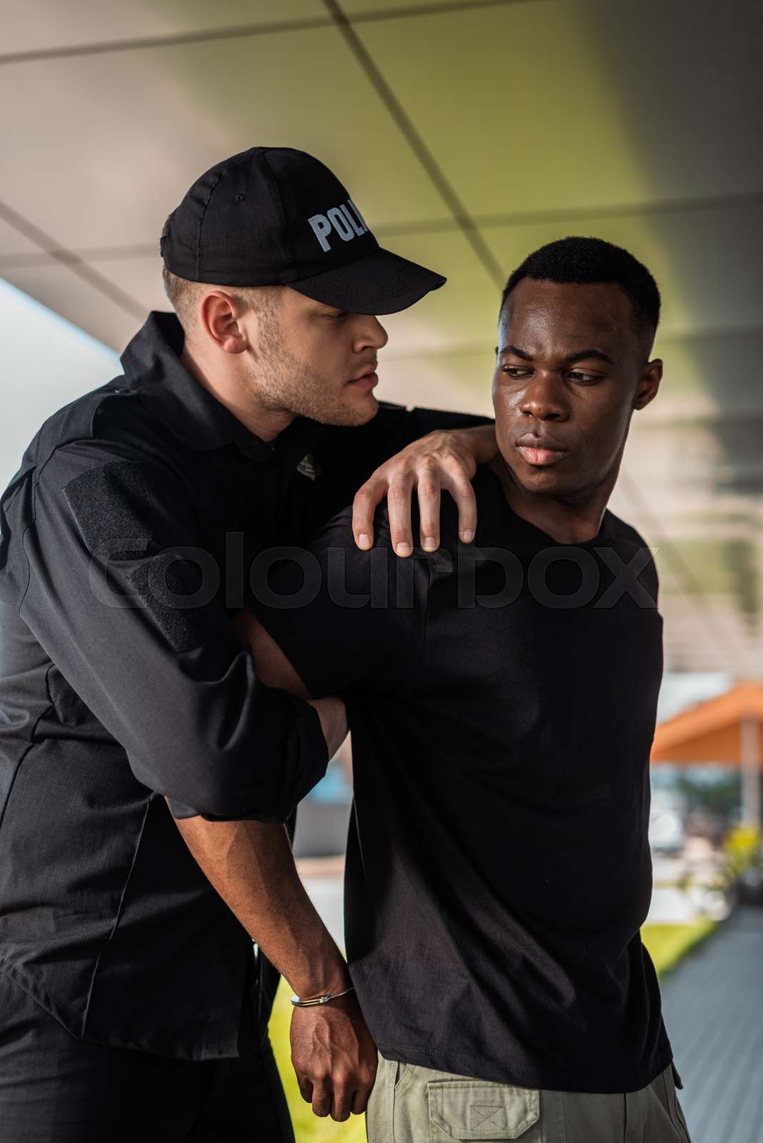 angry police officer in uniform detaining african american man ...