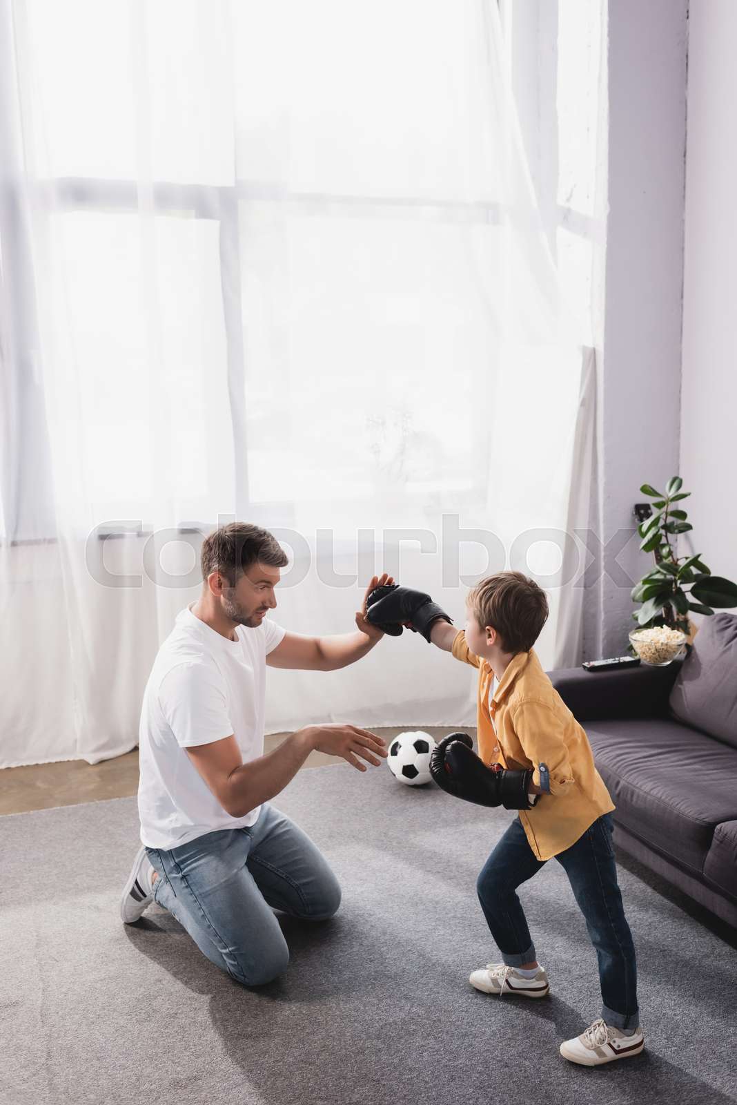 cute boy in boxing gloves fighting with father standing on knees on ...