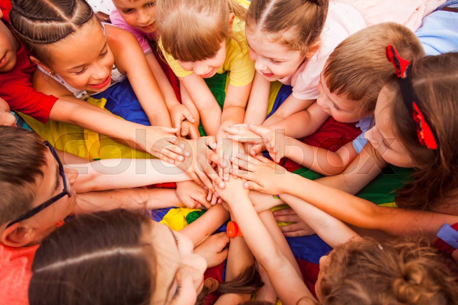 Children holding hands together, laying on a floor | Stock image ...
