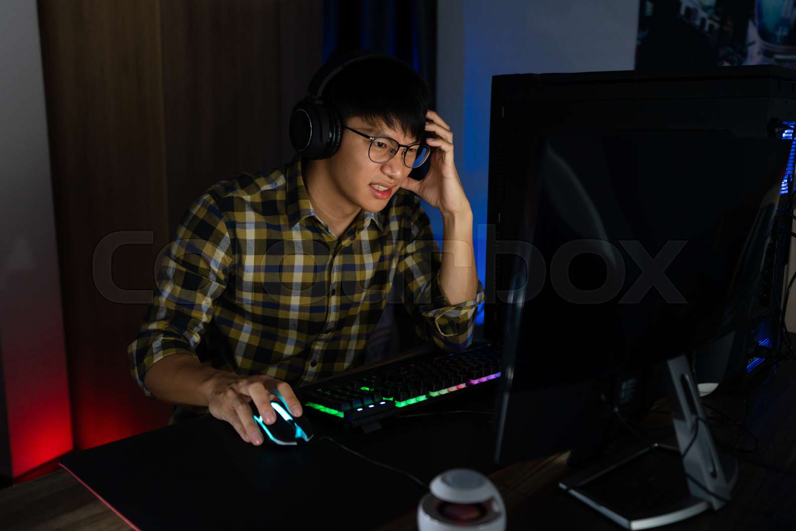 Asian man gamer in headphones stressed with hand feel depressed or ...