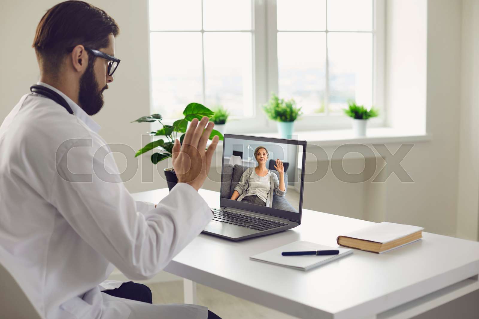 Remote medical consultation. A male doctor consults a woman has a video ...