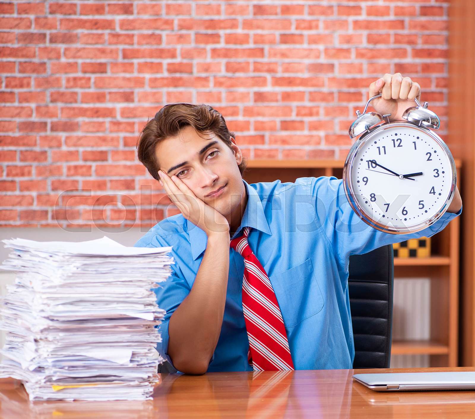 Young employee with excessive work sitting at the office | Stock image ...
