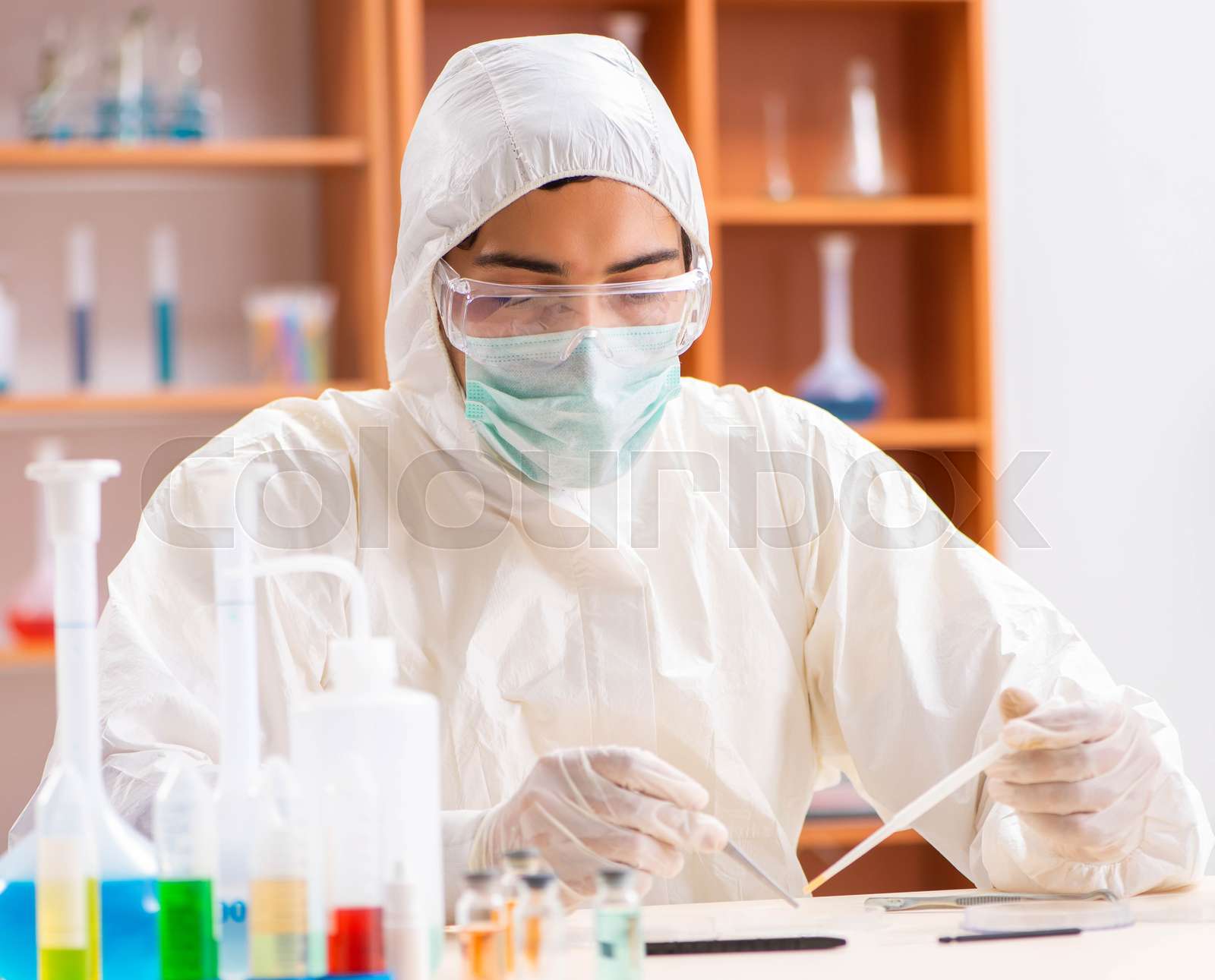 Young biochemist wearing protective suit working in the lab | Stock ...