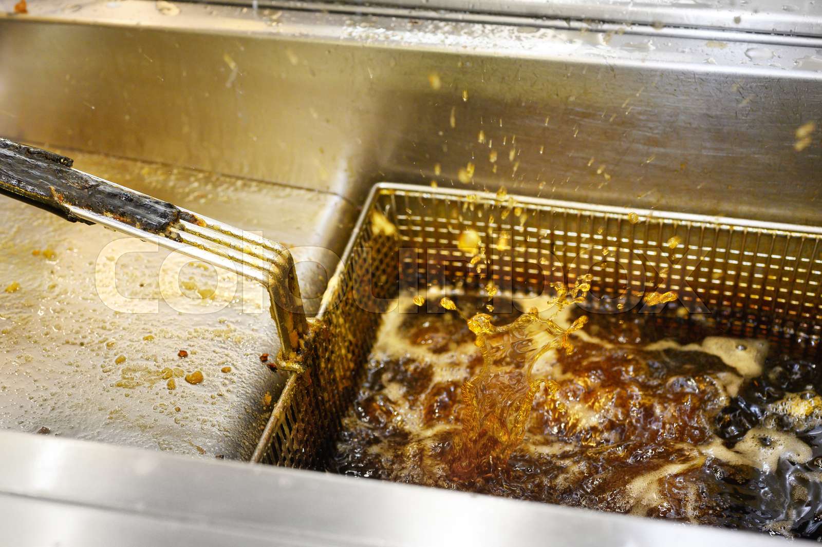 Greasy deep fryer with splashing boiling oil. | Stock image | Colourbox