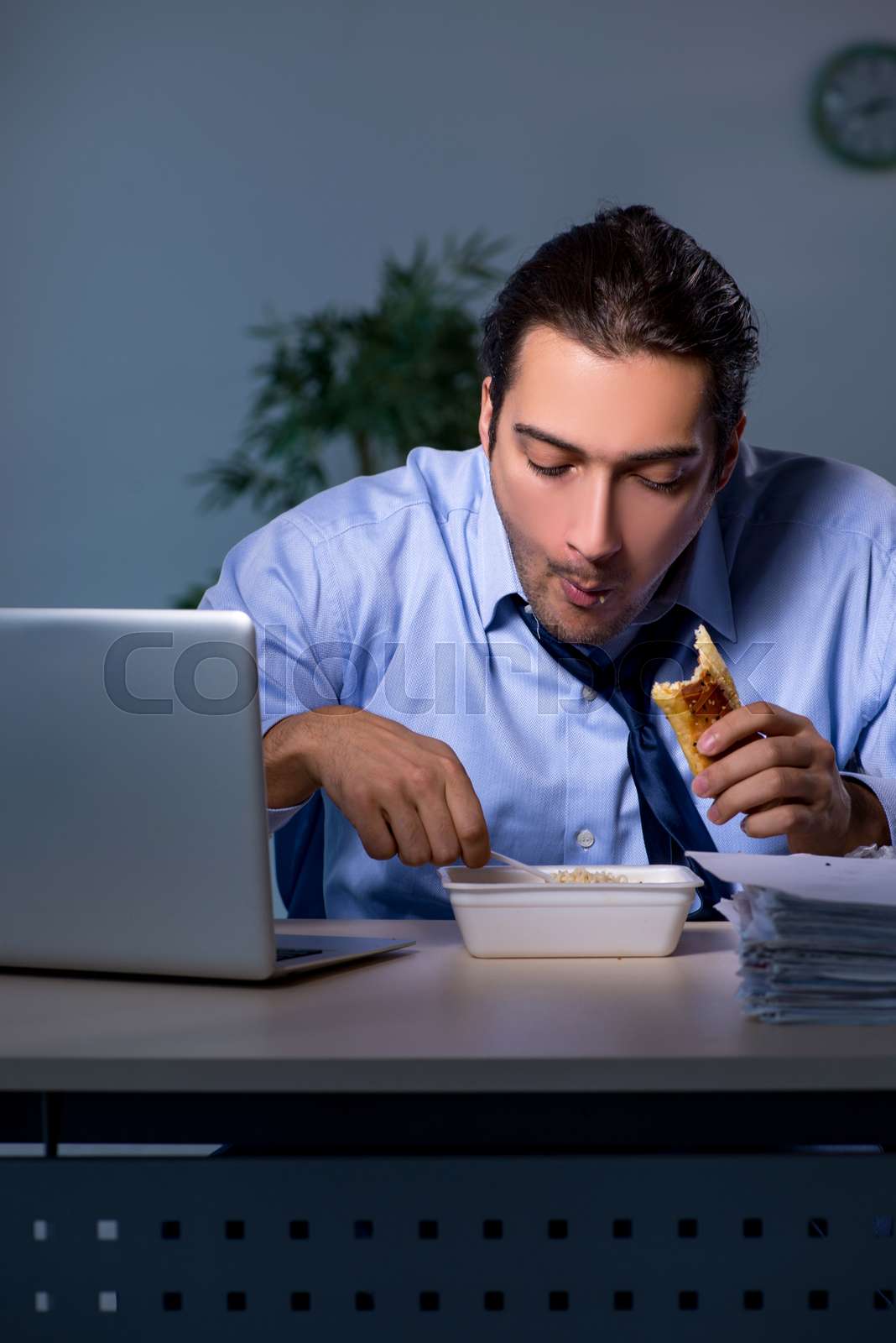 Hungry employee working late in the office | Stock image | Colourbox