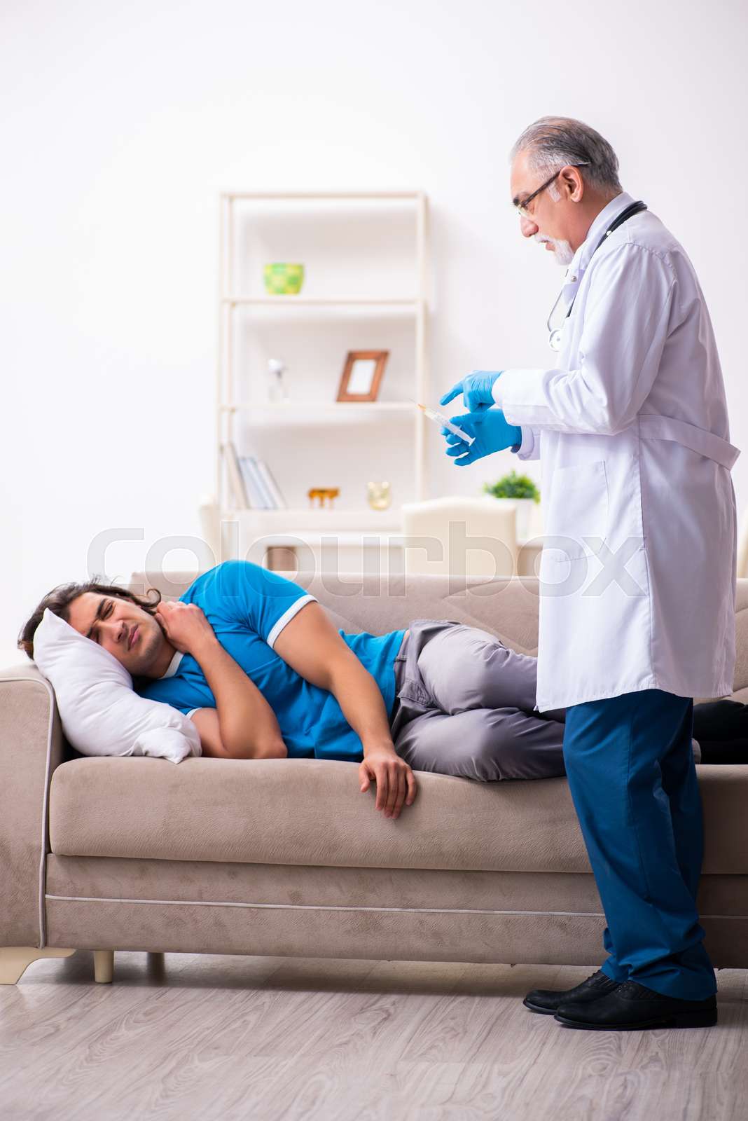 Two doctors visiting sick young man at home | Stock image | Colourbox