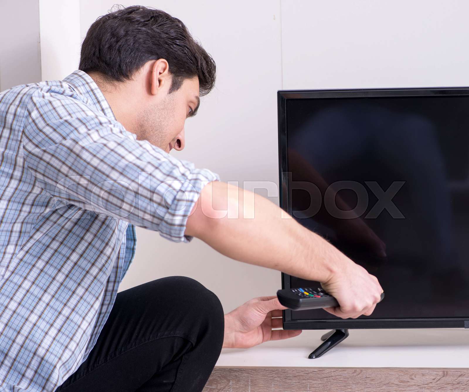 Man trying to fix broken tv | Stock image | Colourbox
