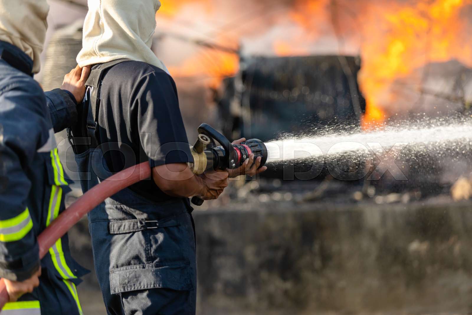Firefighter spraying water from big water hose to prevent fire | Stock ...