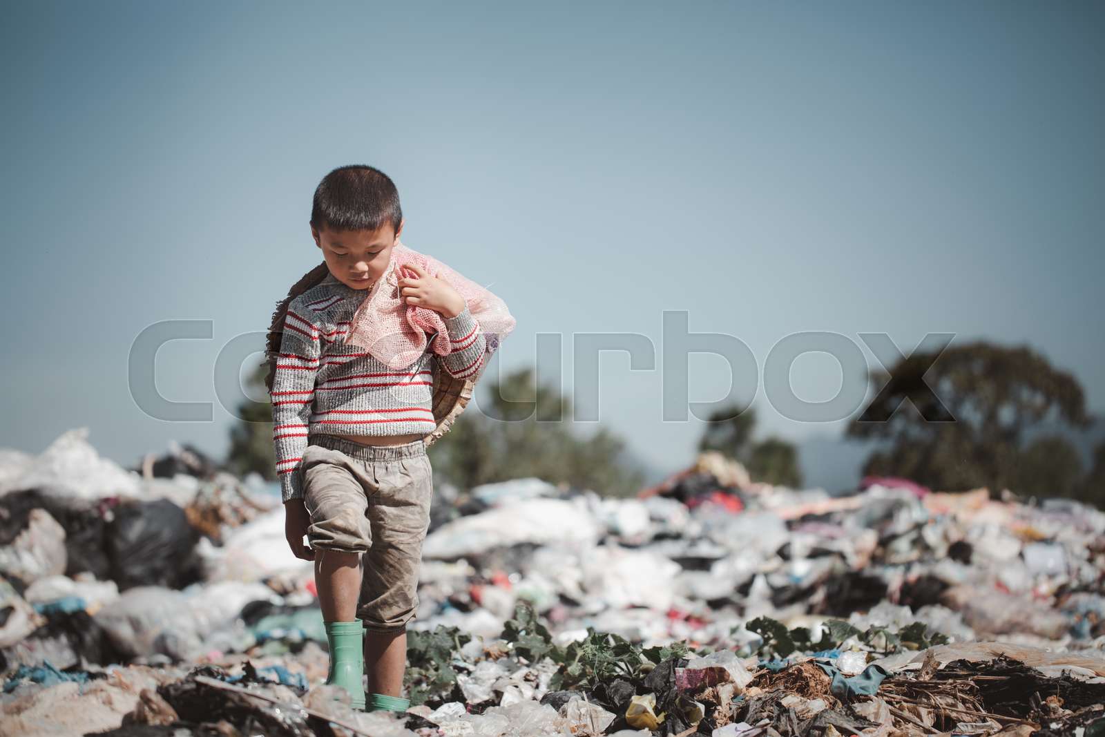 A poor boy collecting garbage waste from a landfill site in the ...