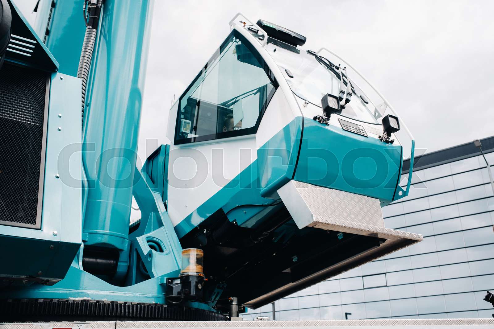 a cab with the operator of a Large blue car crane that stands ready to ...
