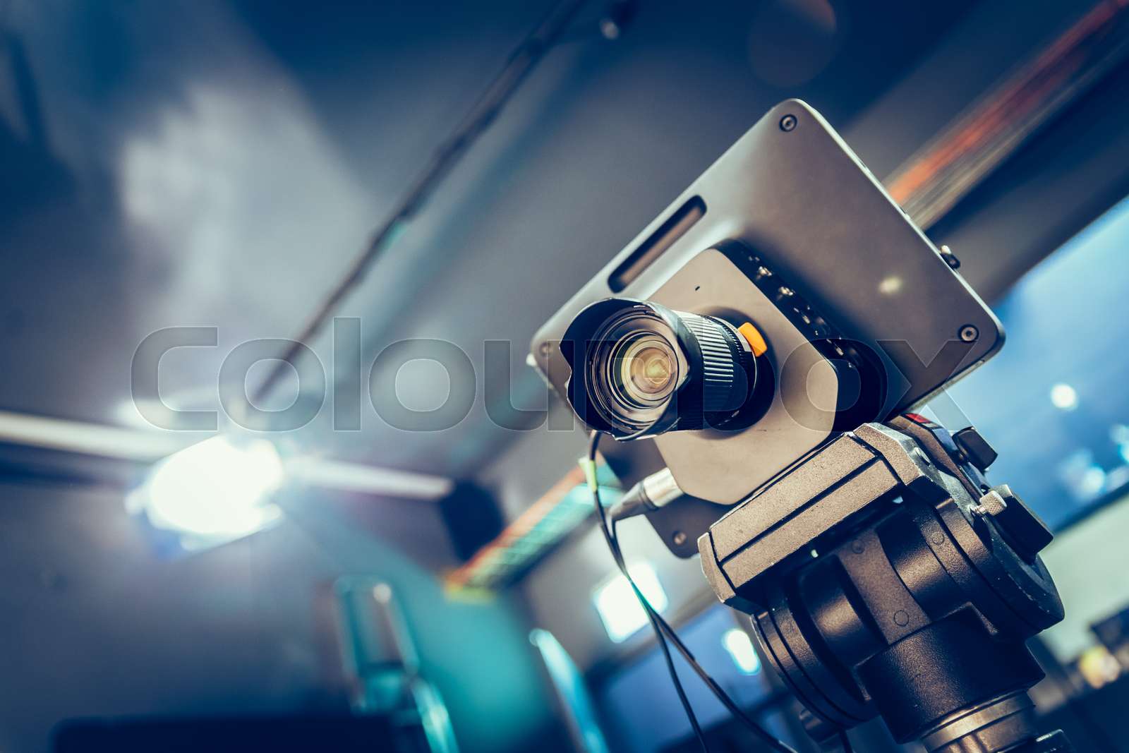 Modern film camera on a tripod in a broadcasting studio, spotlights and ...