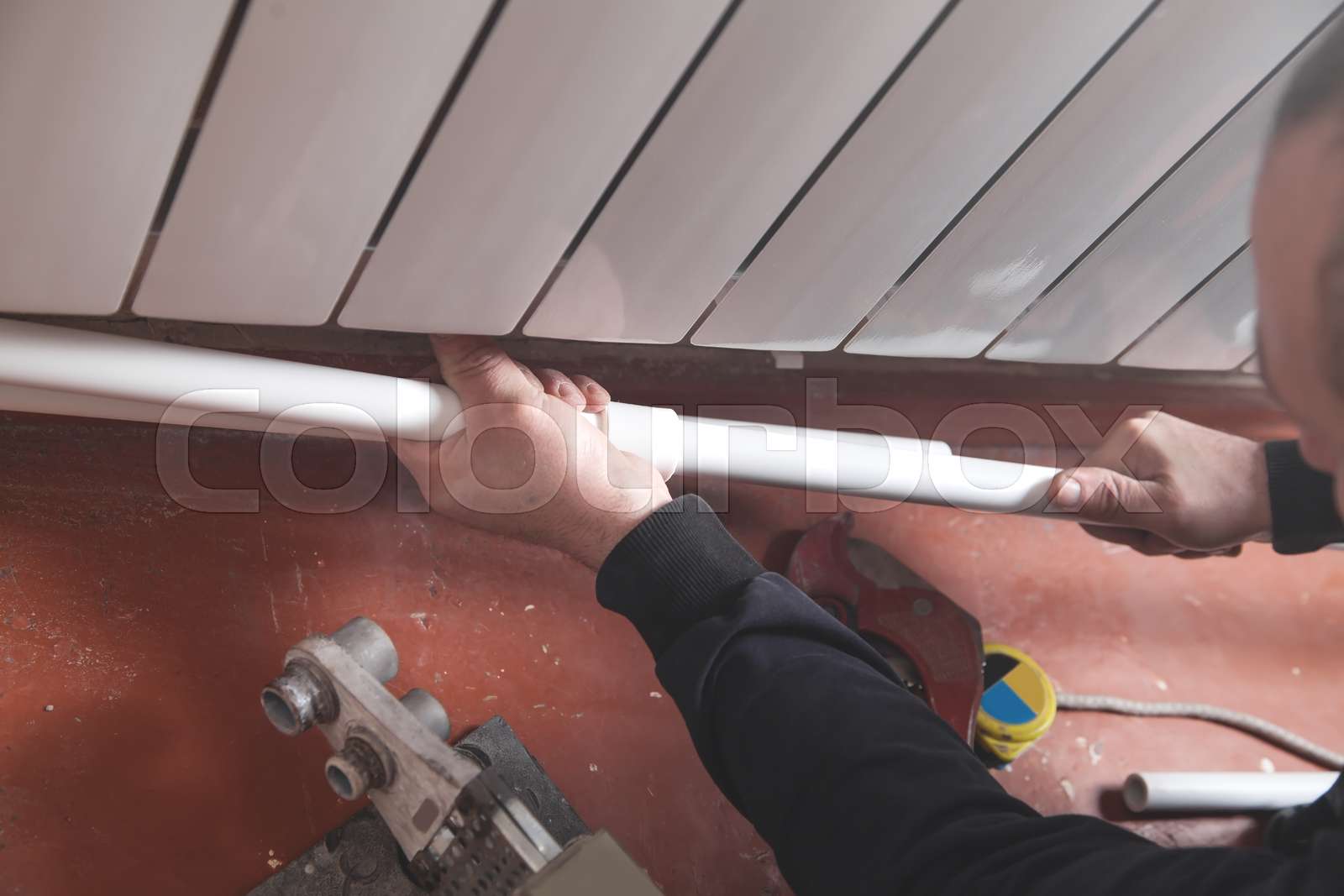 Worker connecting plastic pipe. Installing water heating radiator ...