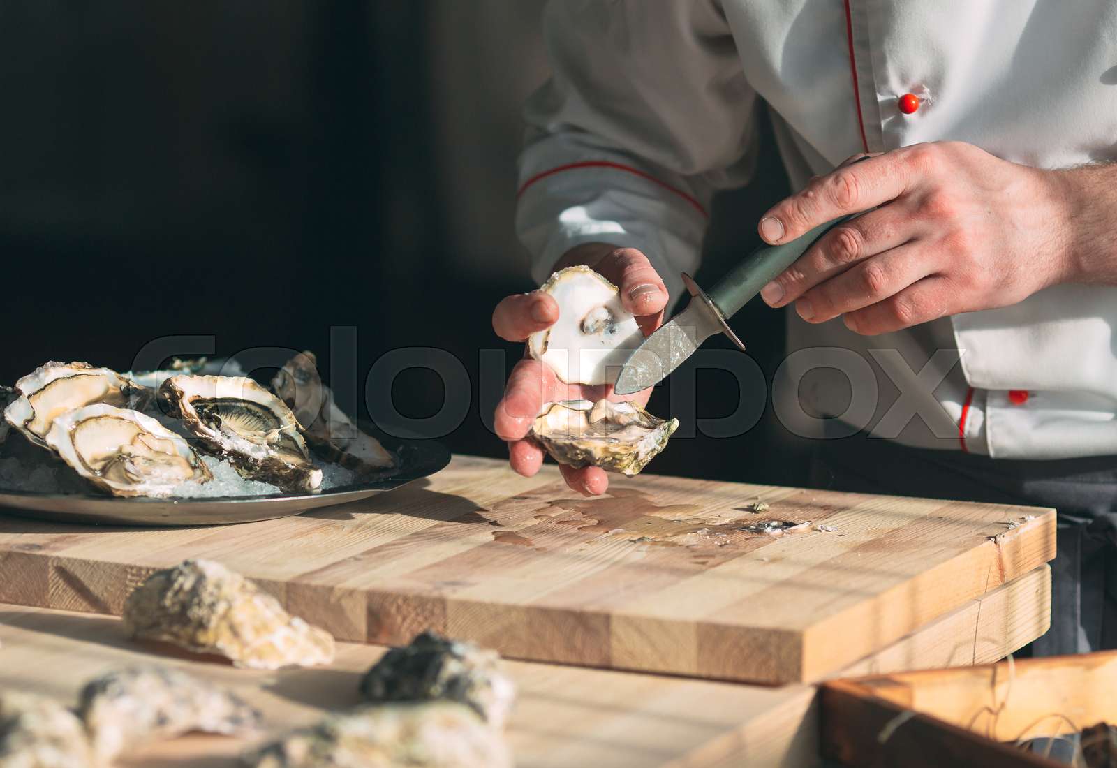Opening the hollow and flat oysters. Chef opens oysters in the ...
