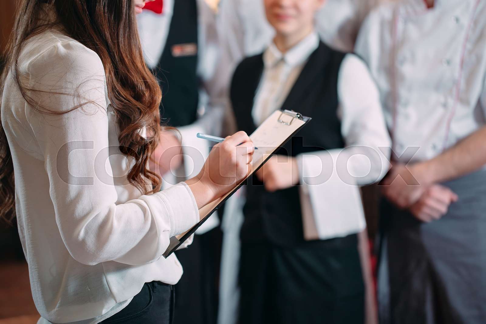 restaurant manager and his staff in kitchen. interacting to head chef ...