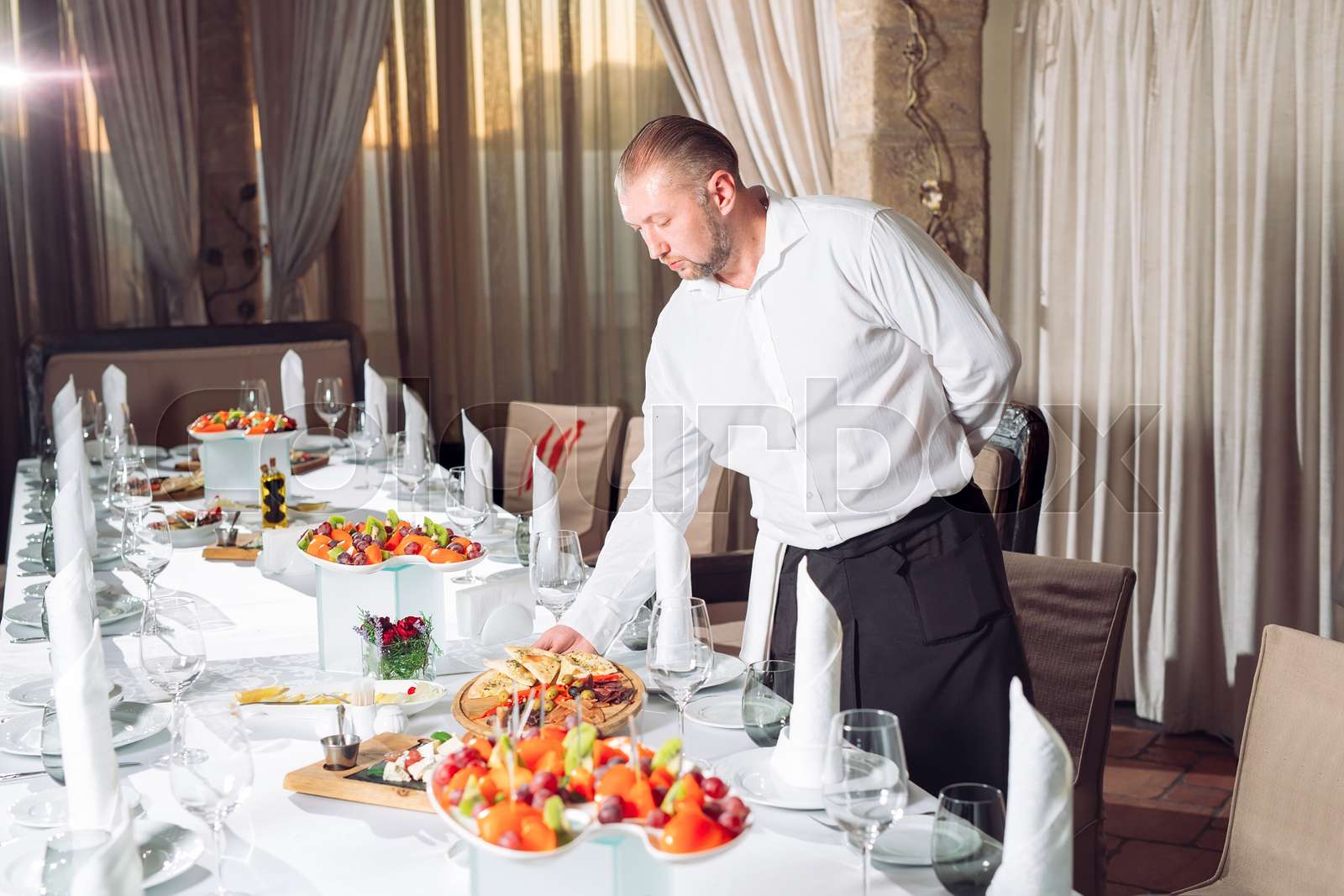 Waiter serving table in the restaurant preparing to receive guests ...