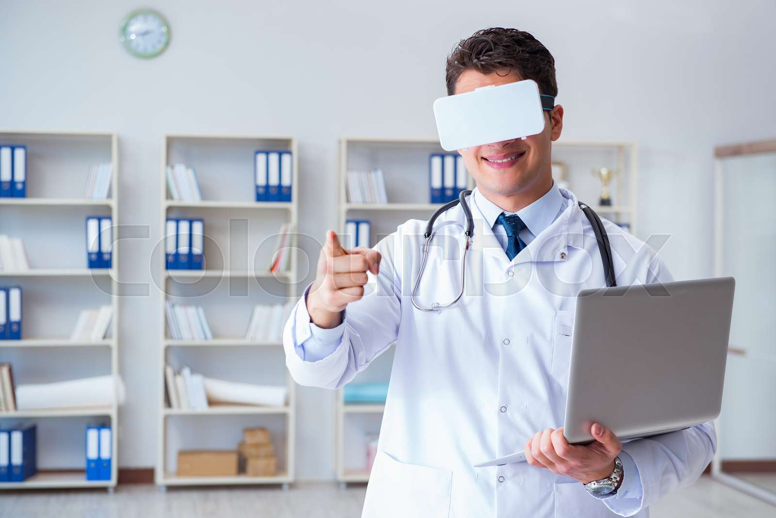 Young doctor with vr virtual reality headset working in the offi ...