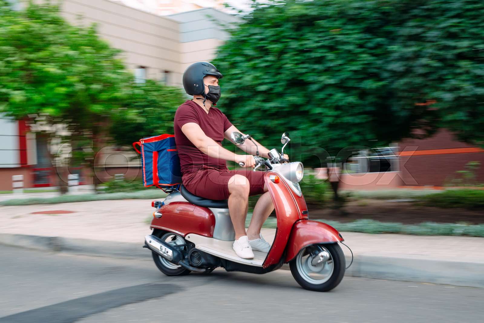Delivery boy wearing red uniform on scooter with isothermal food case ...