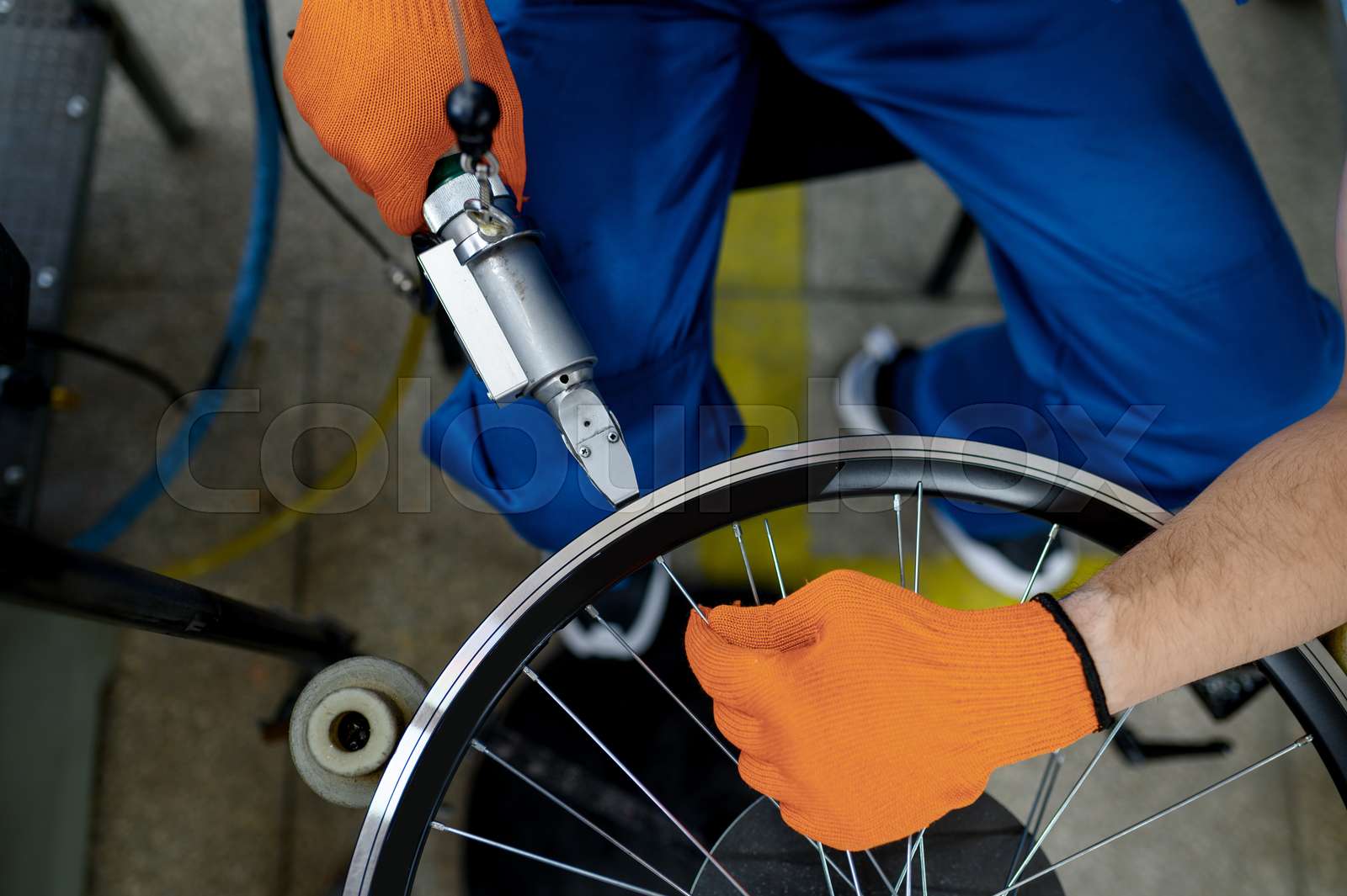 Worker with machine tool installs new bicycle rim | Stock image | Colourbox