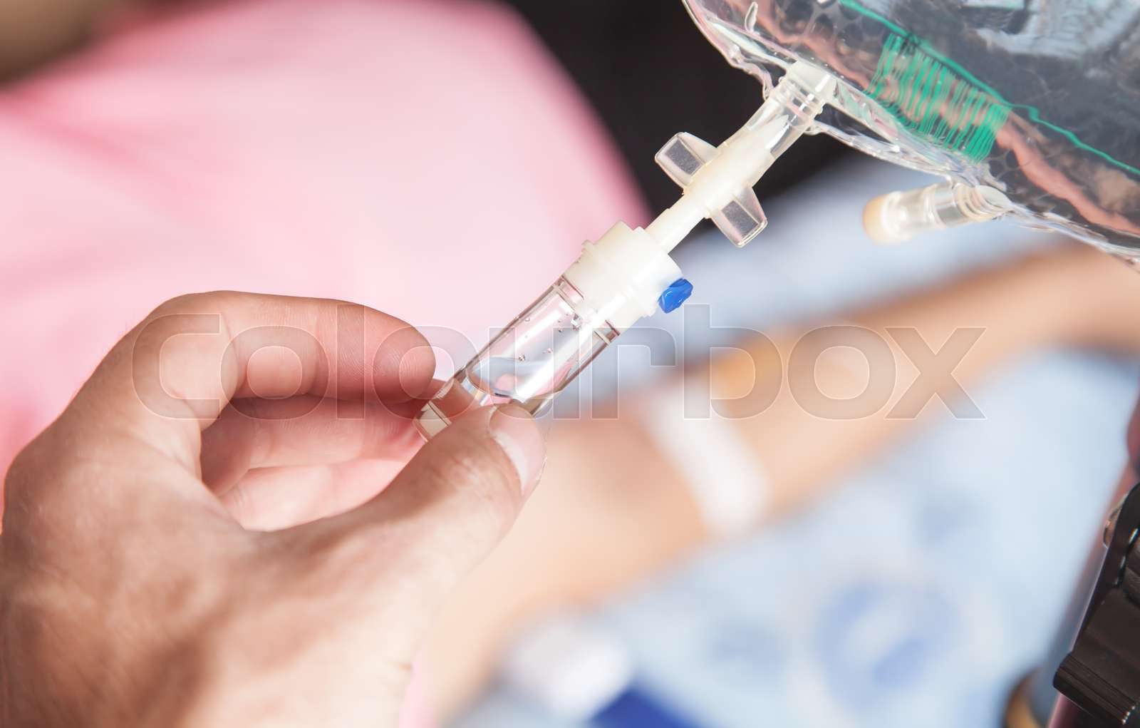 Male hand connecting an intravenous drip in home. | Stock image | Colourbox