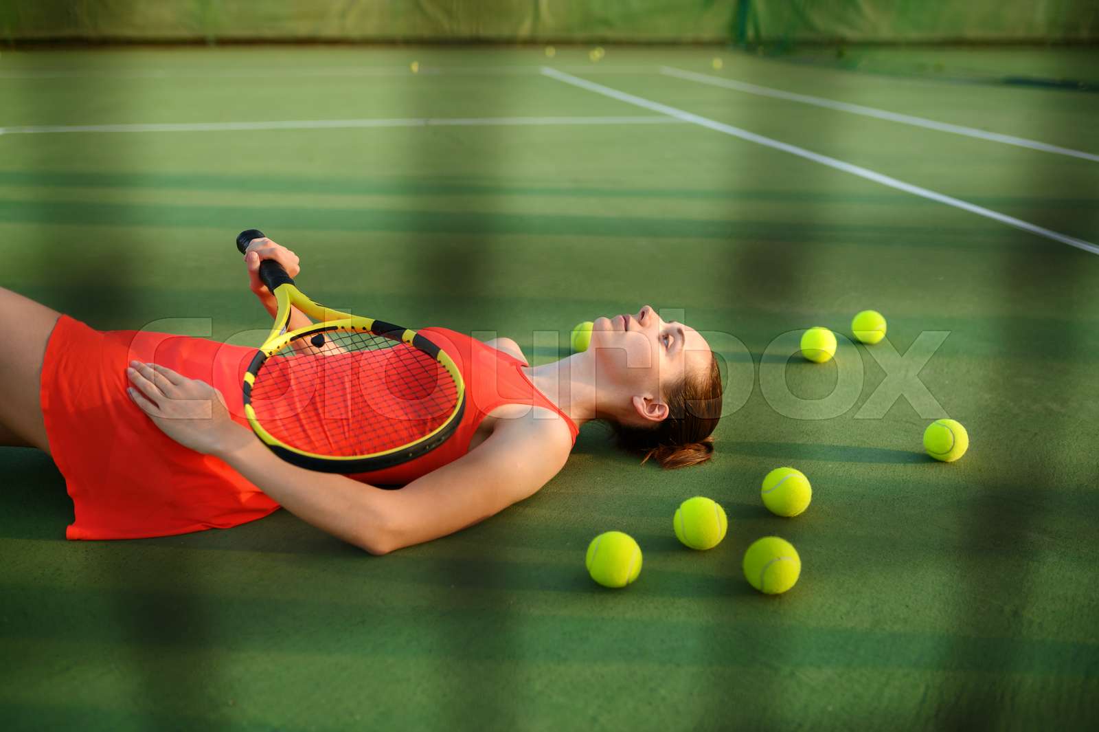Tired female tennis player lies on court | Stock image | Colourbox