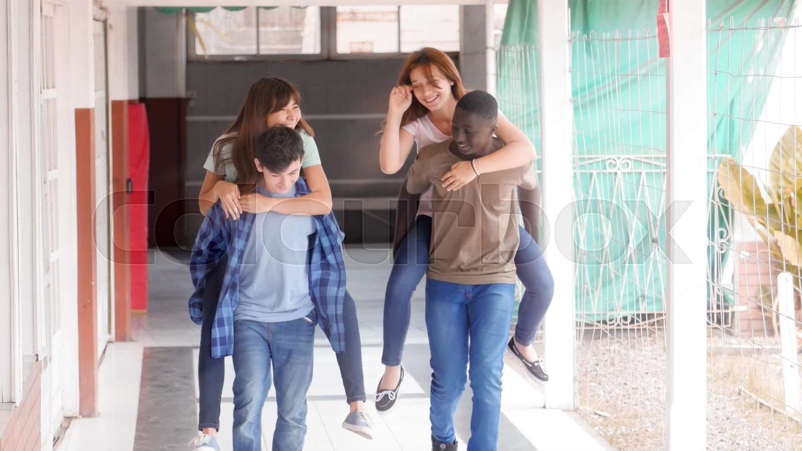 Group of teenager playing piggyback in the school hallway | Stock video ...