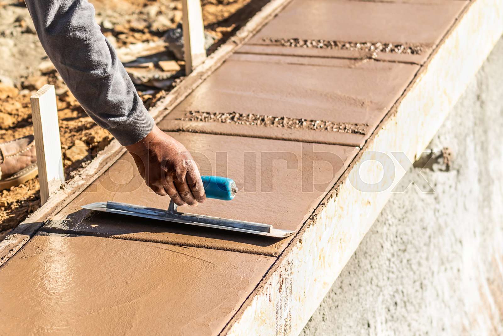 Construction Worker Using Trowel On Wet Cement Forming Coping Around ...
