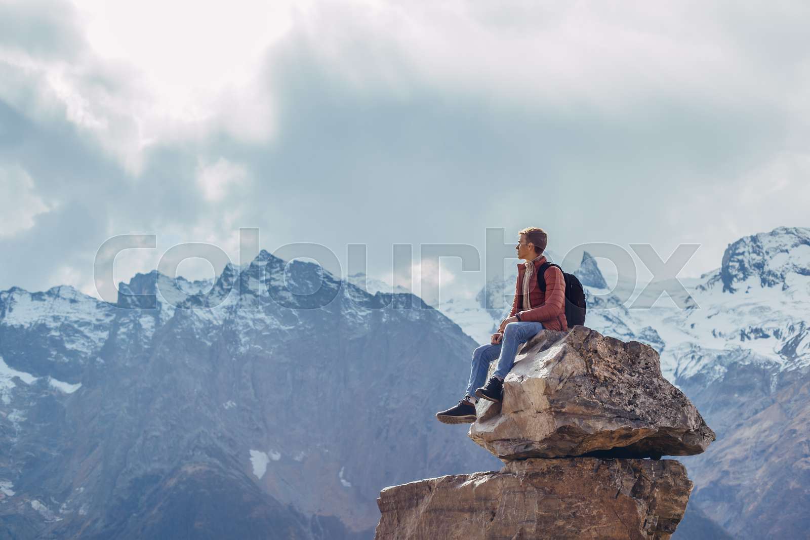 Young guy sitting on mountain peak | Stock image | Colourbox