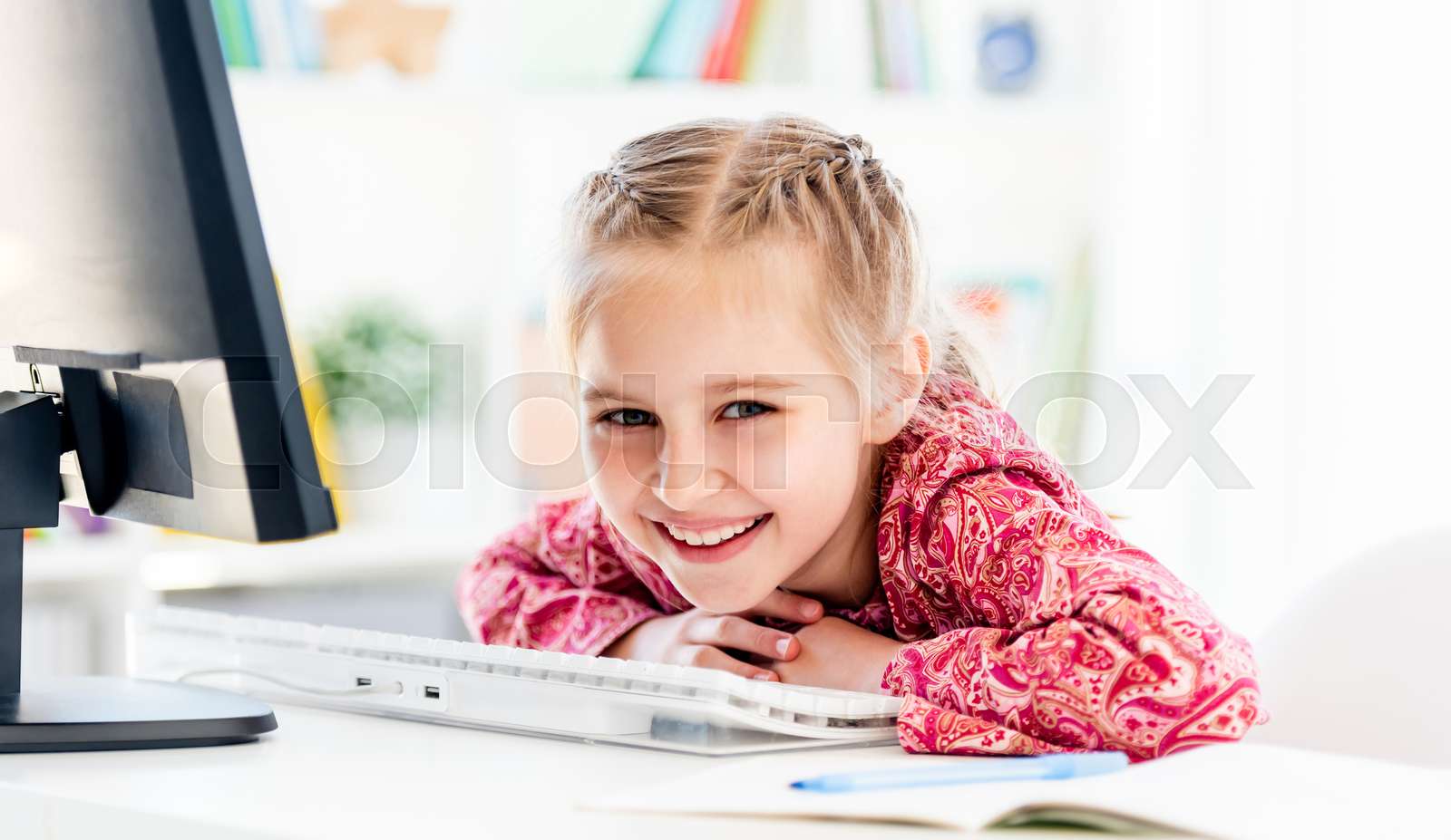Smiling little girl at computer desk | Stock image | Colourbox