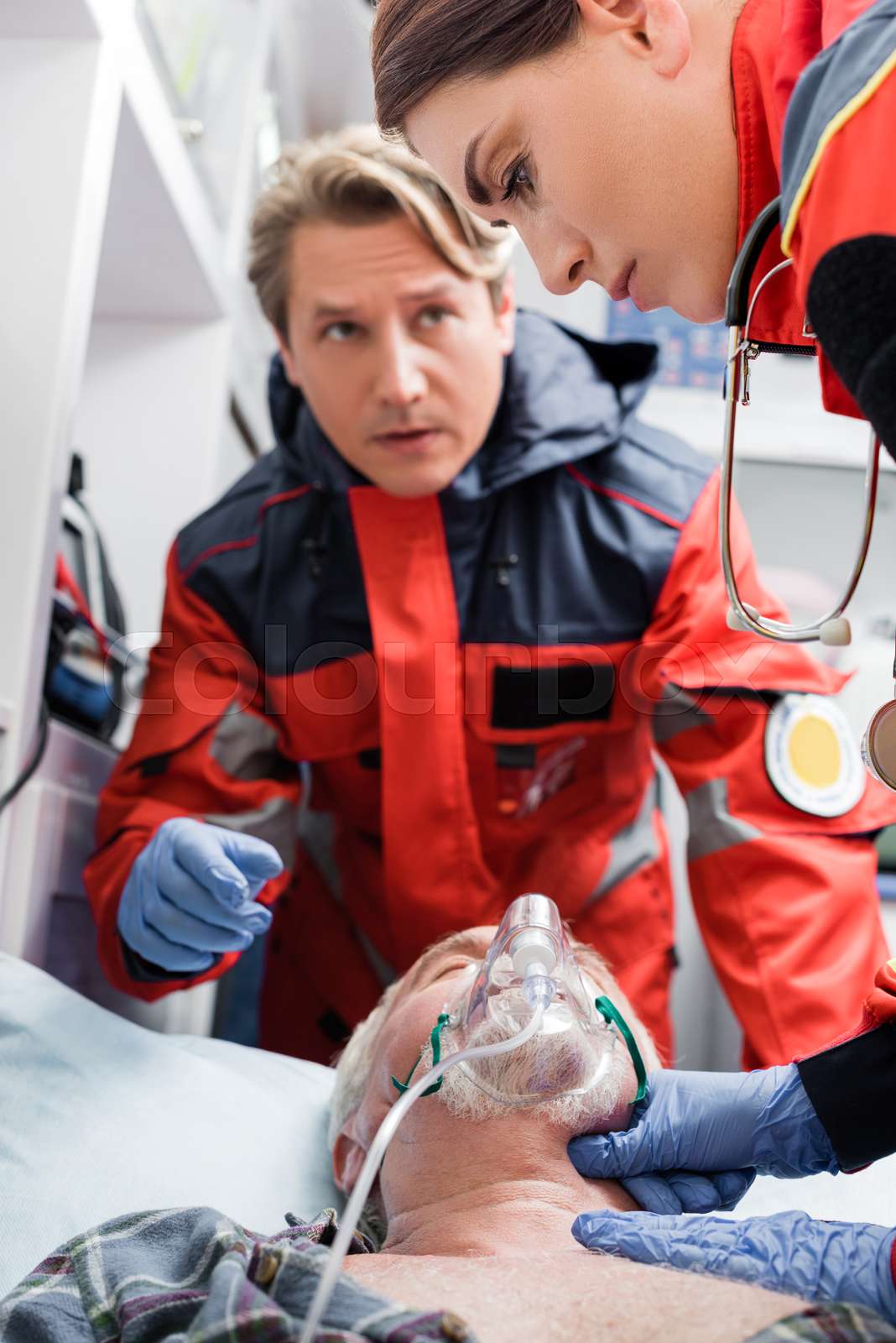 Selective focus of paramedic checking pulse of patient in oxygen mask ...