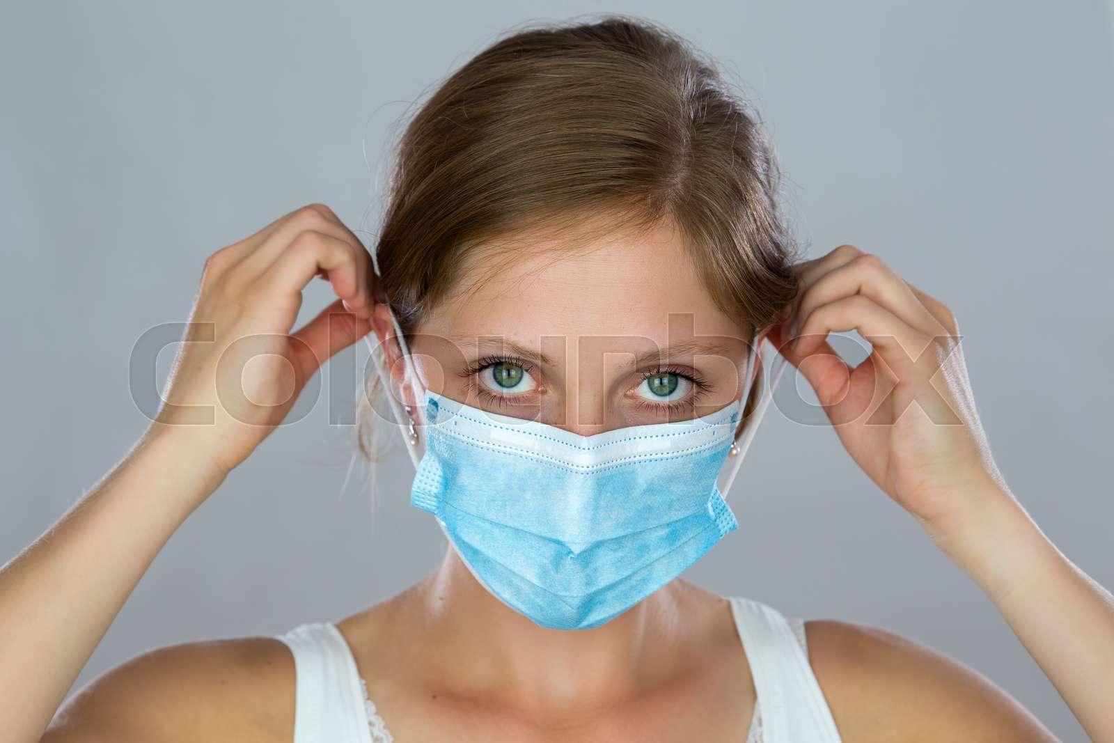 Young woman putting on face mask during pandemic. | Stock image | Colourbox