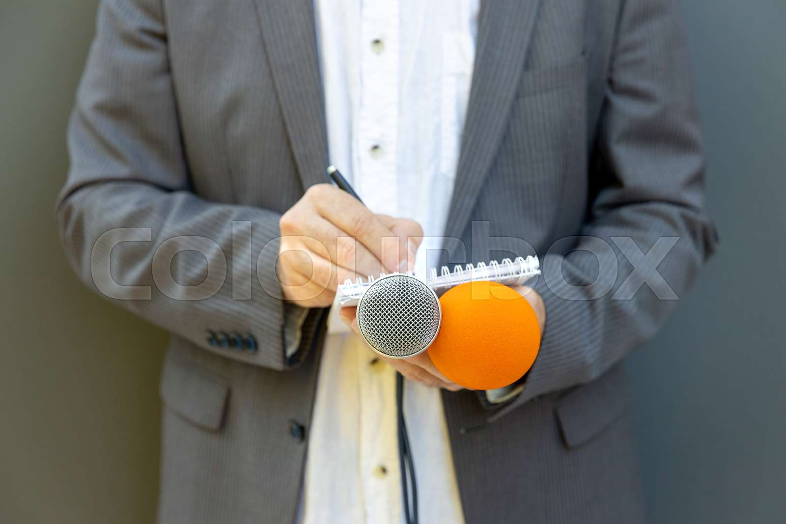 Male journalist at news conference or media event, holding microphone ...