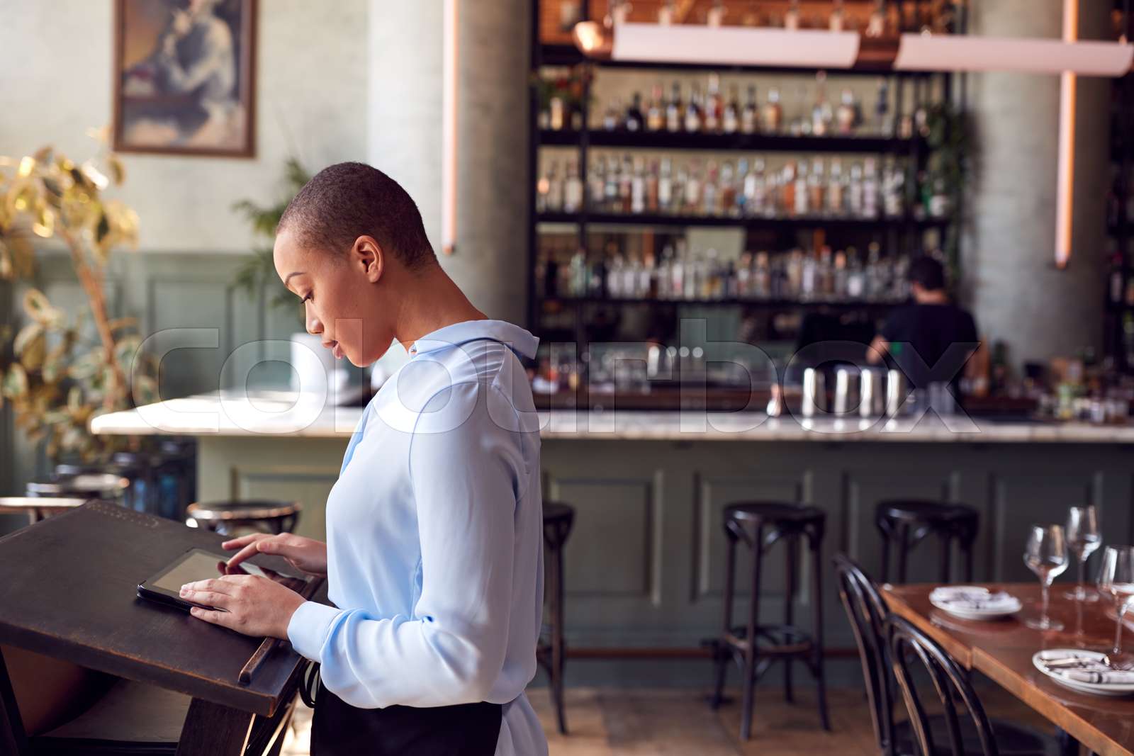 Female Owner Of Restaurant Bar Standing At Counter Using Digital Tablet ...