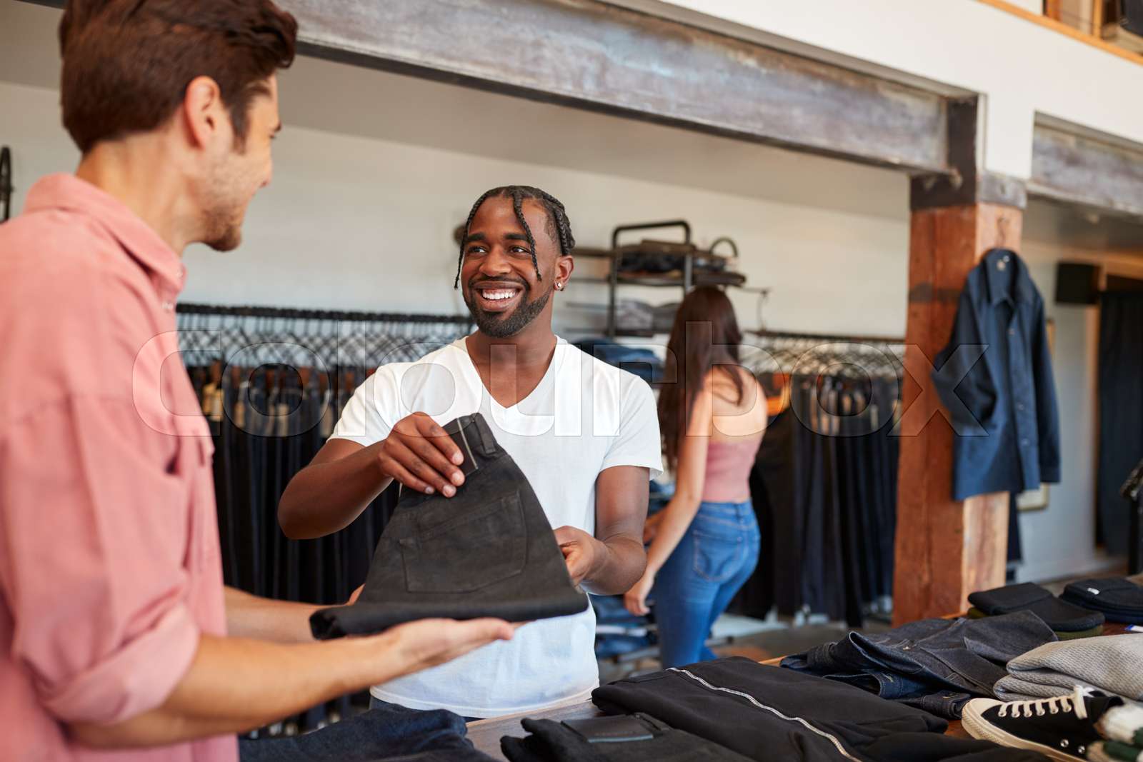 Smiling Sales Assistant Helping Male Customer To Buy Clothes In Fashion ...