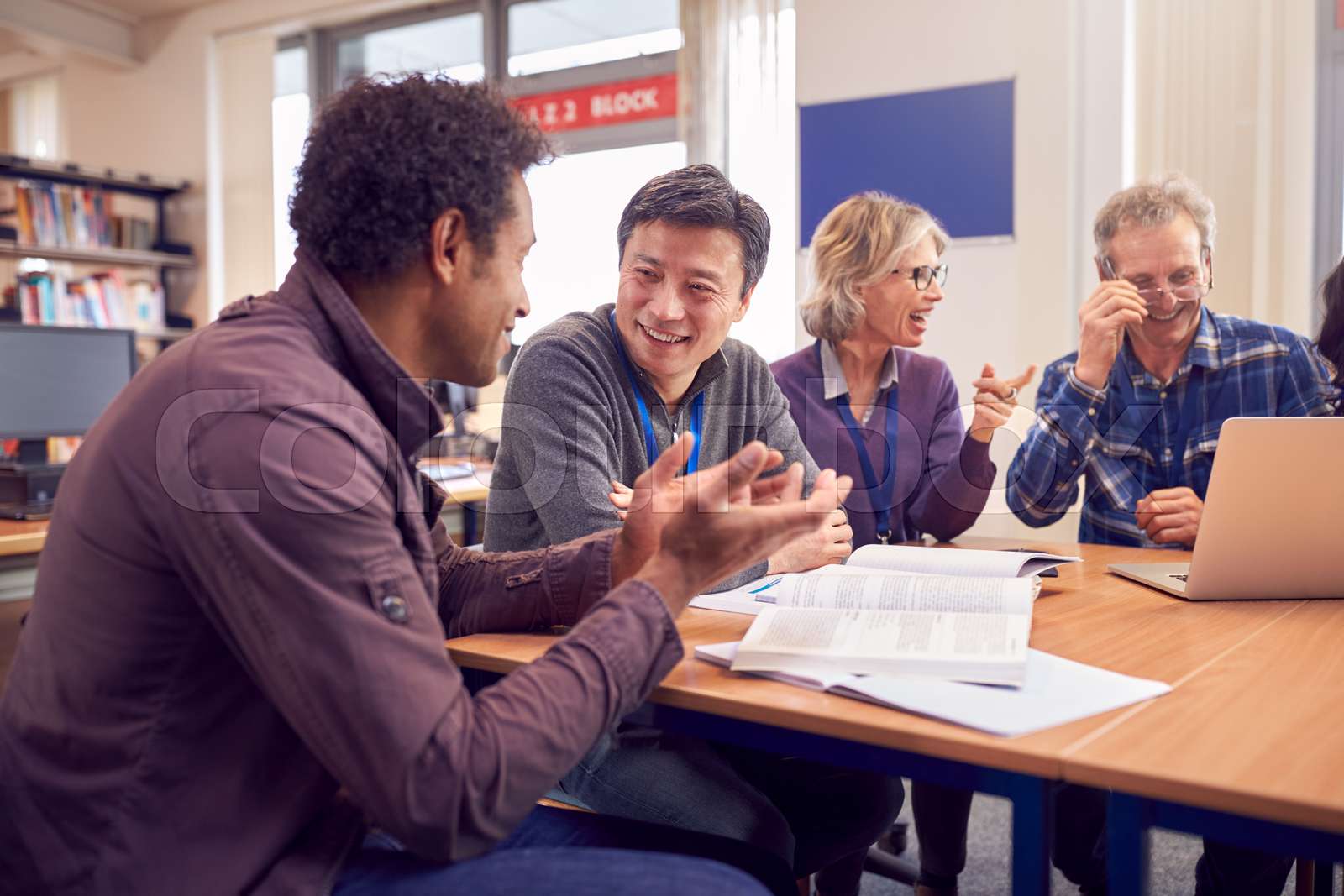 Teacher With Group Of Mature Adult Students In Class Sit Around Table ...