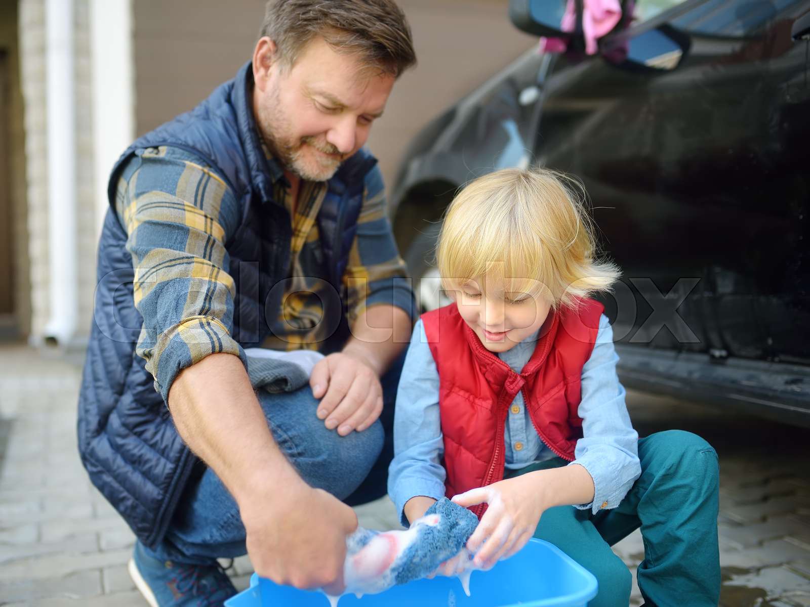 Preschooler boy helping his father washing family car. Little dad ...