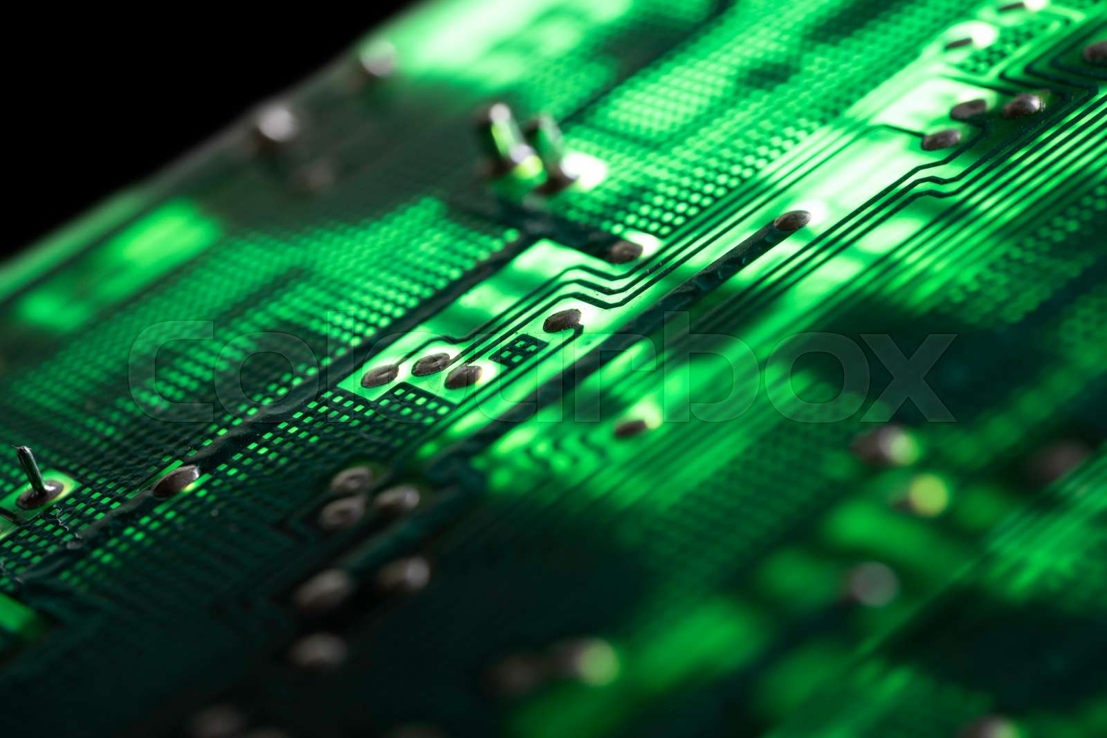 Detail of an illuminated green electronic circuit board with many ...