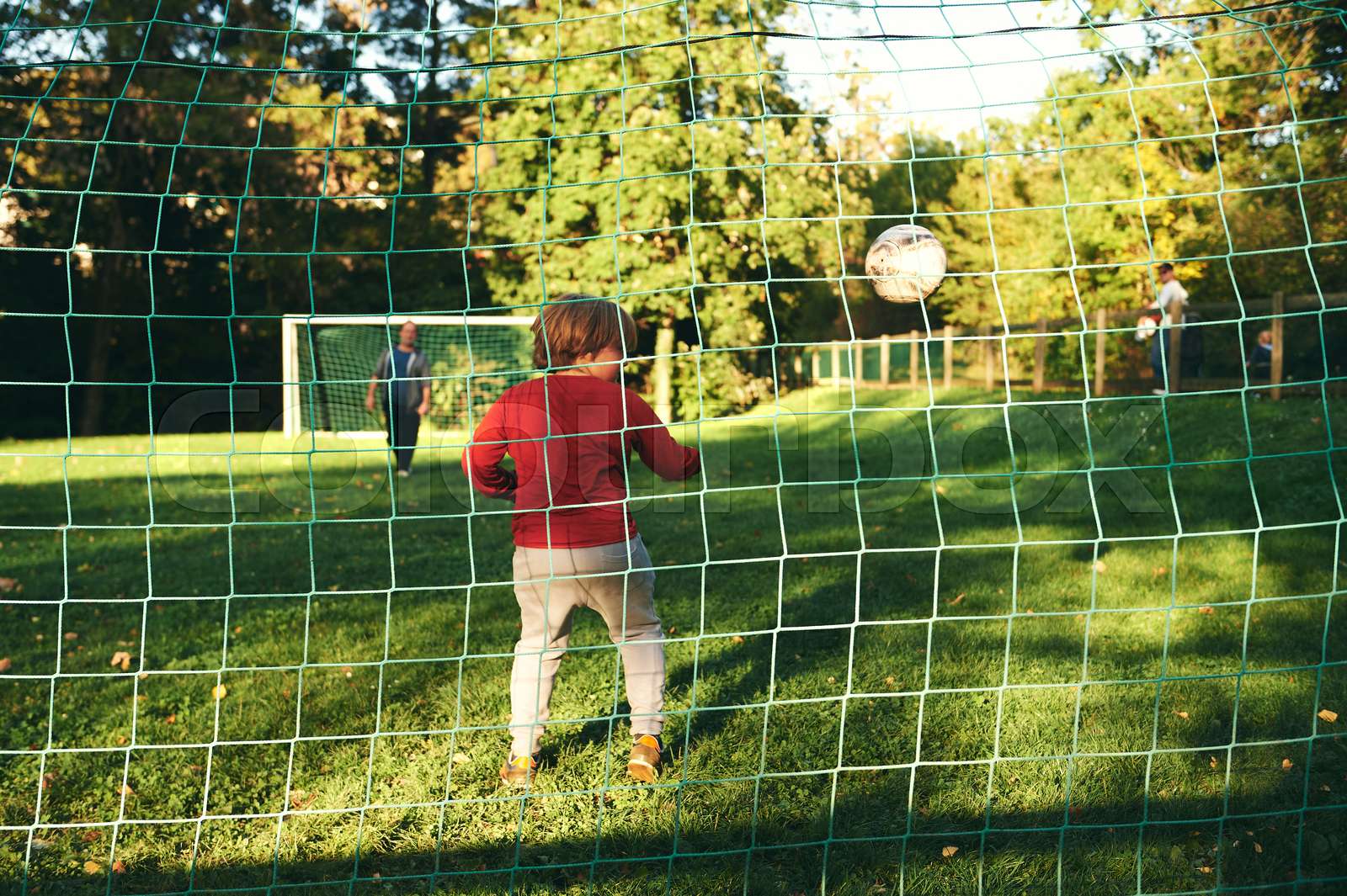 Little boy playing football with his father, kid goalkeeper defending ...