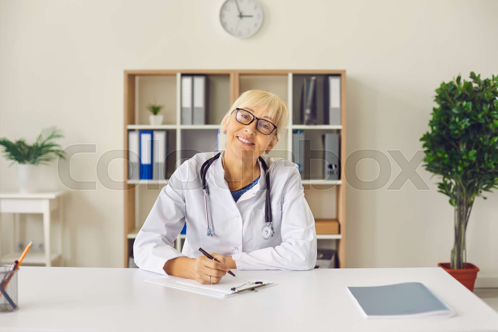 Female family doctor sits in front of the camera and gives an online ...