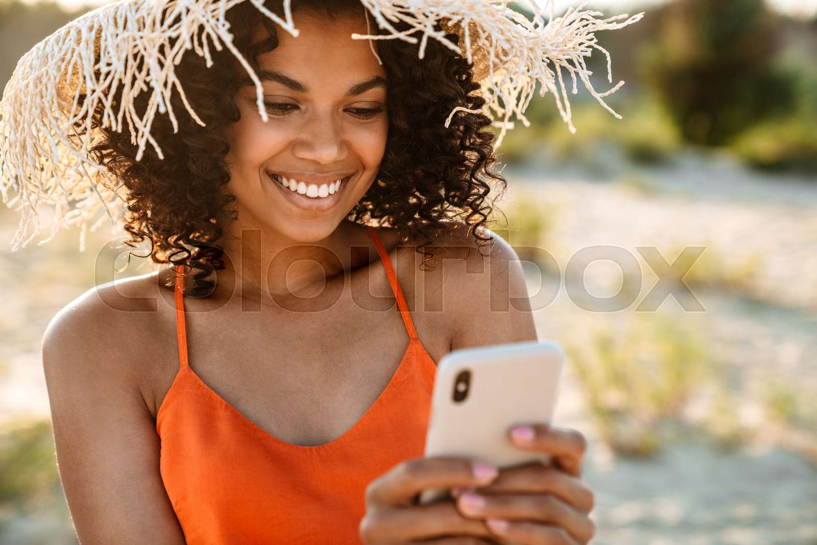 Smiling young african woman using mobile phone | Stock image | Colourbox