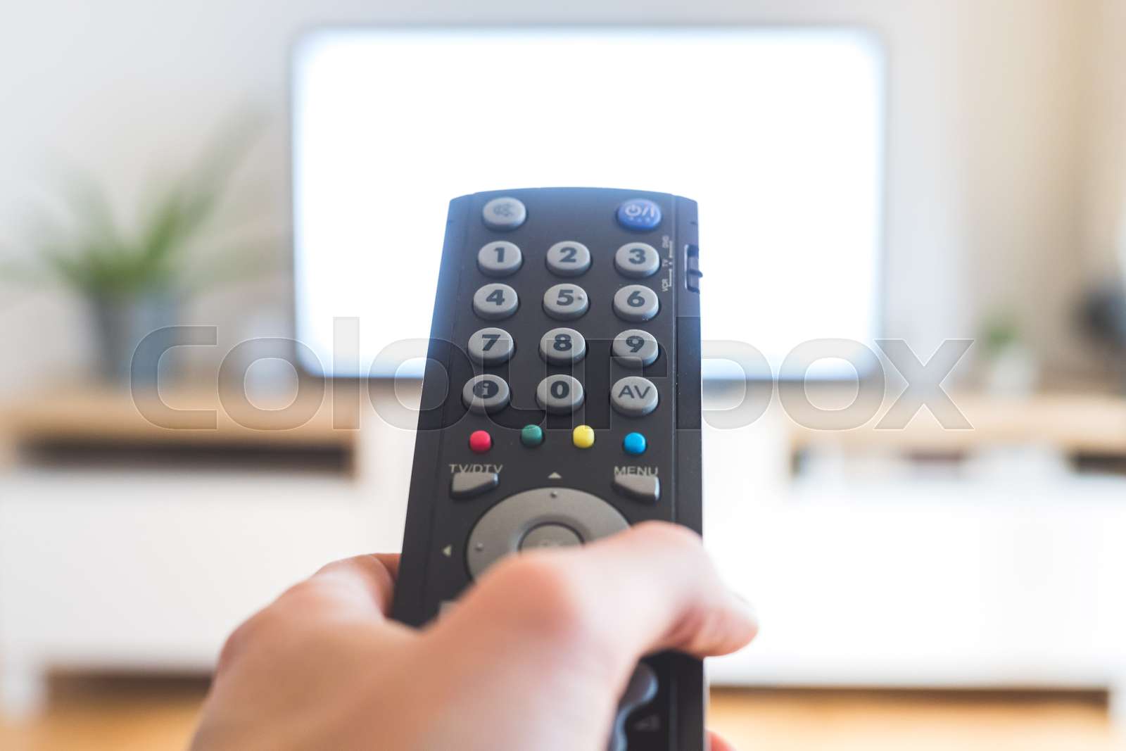 Male hand is holding TV remote control, streaming on a smart TV ...