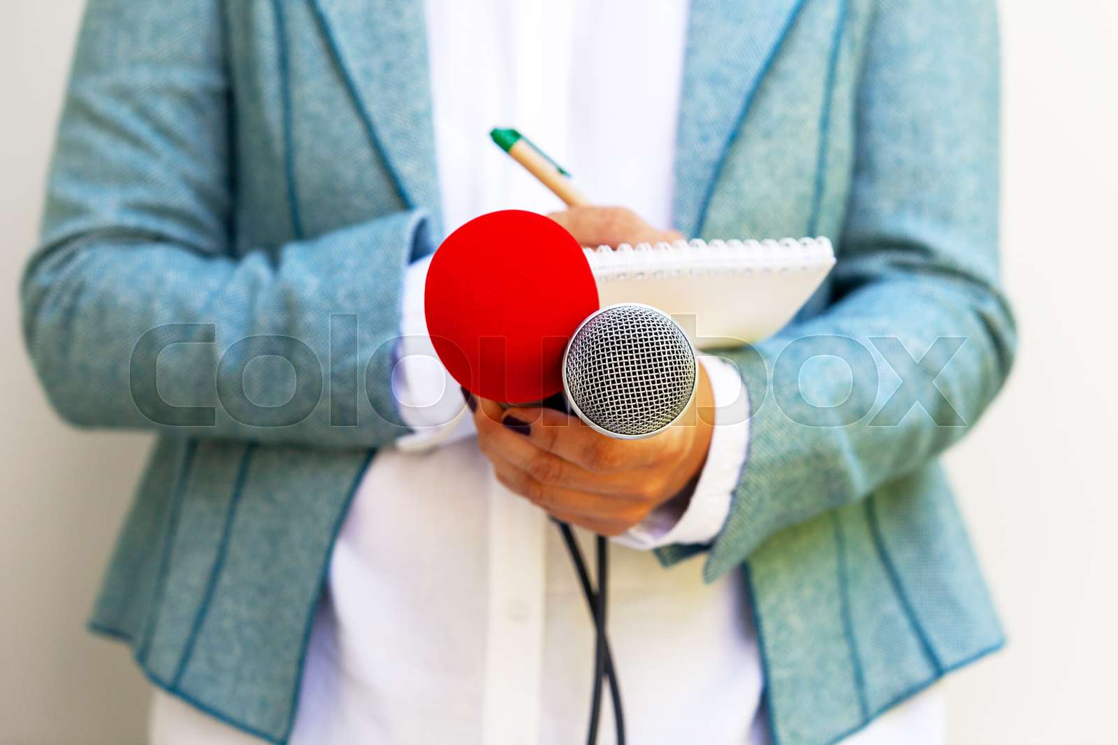 Female journalist at news conference, writing notes, holding microphone ...